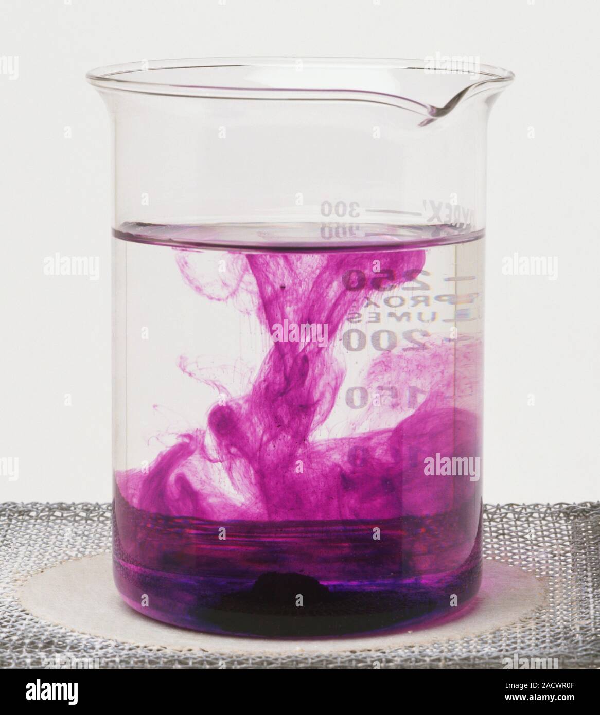 Glass beaker containing potassium manganate shows the solid dissolving ...
