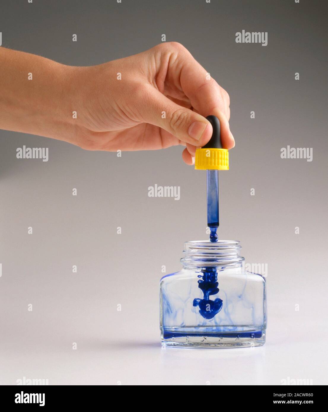 Adding blue ink to bottle of hot water, using dropper, close-up Stock ...