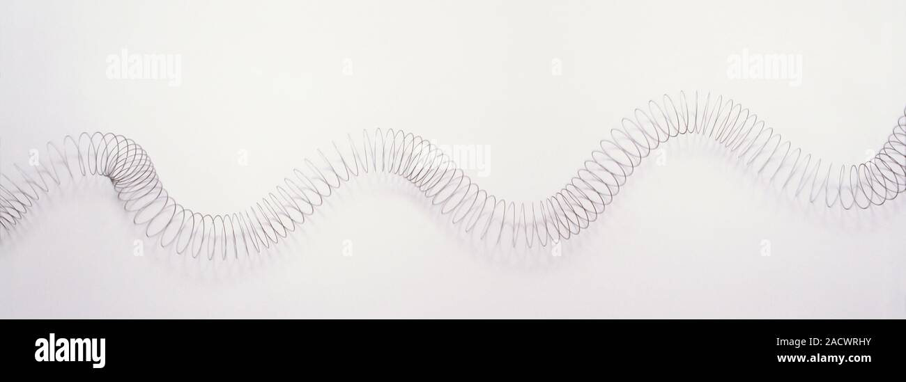 Metal slinky coil manipulated into wavy line to illustrate movement of ...