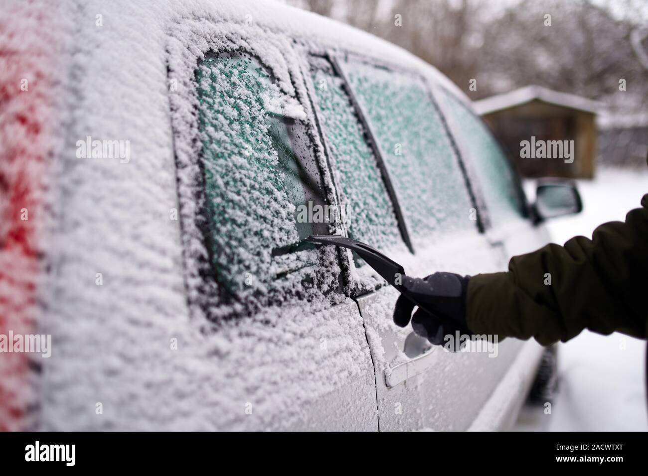 Cleaning the side car windows of snow with ice scraper before the trip ...