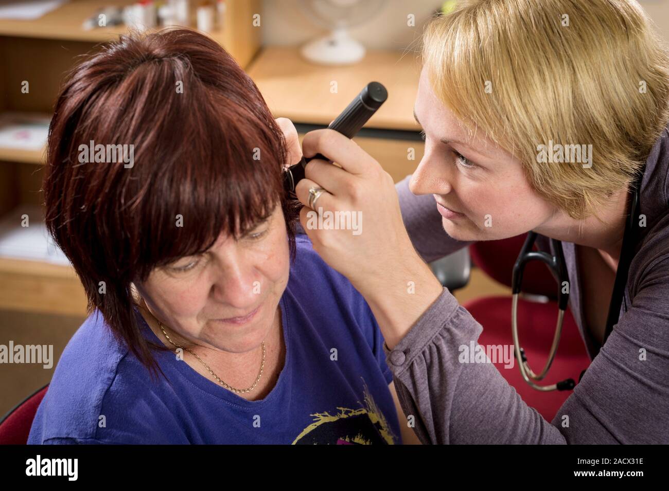 General practice (GP) examining a patient's ear using an otoscope Stock ...