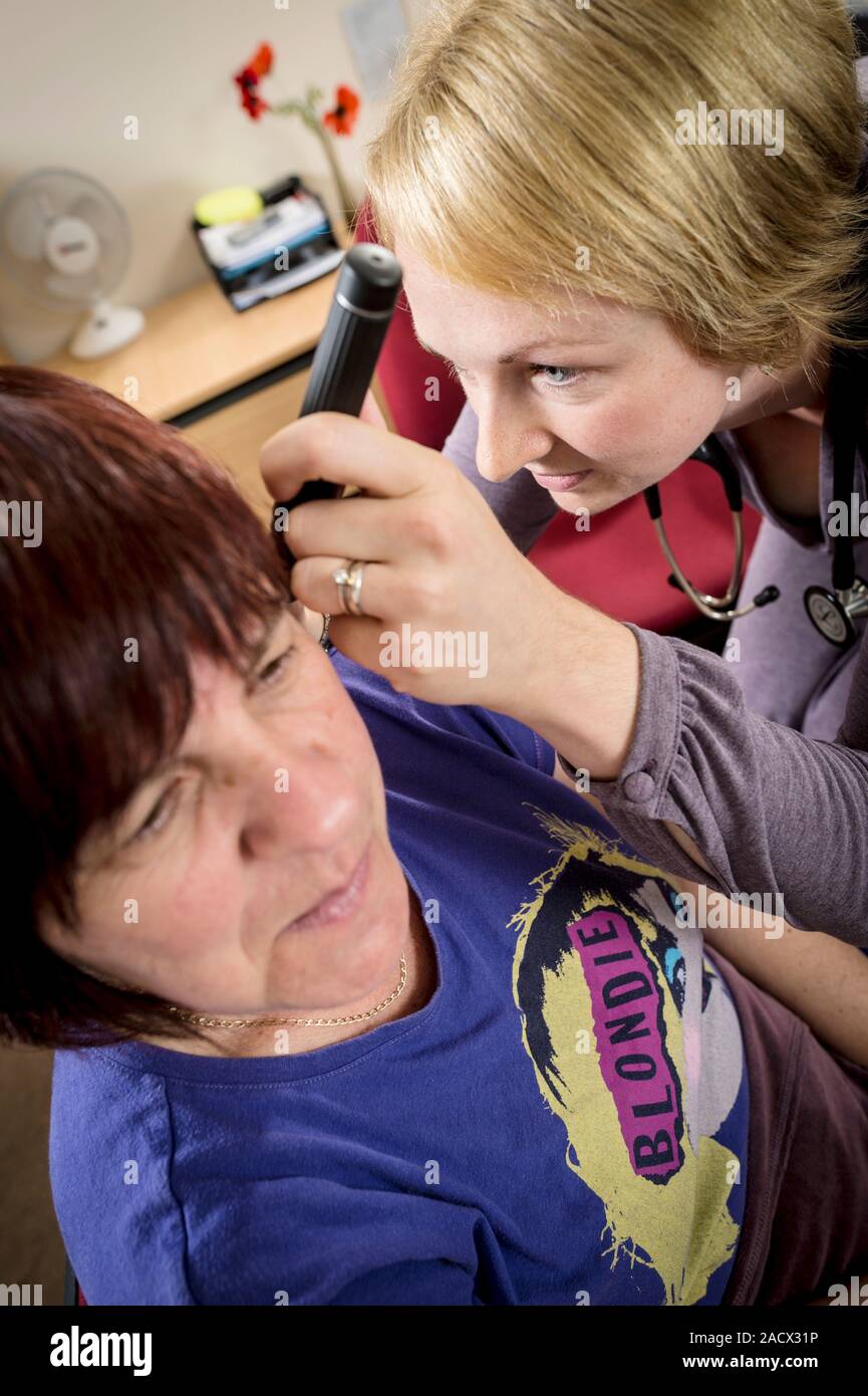 General practice (GP) examining a patient's ear using an otoscope Stock ...