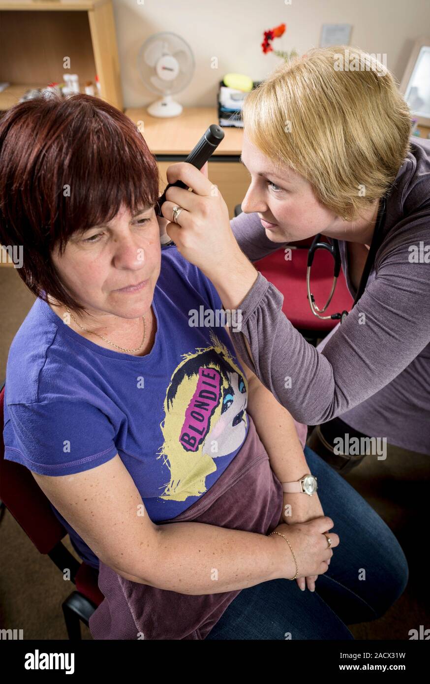 General practice (GP) examining a patient's ear using an otoscope Stock ...