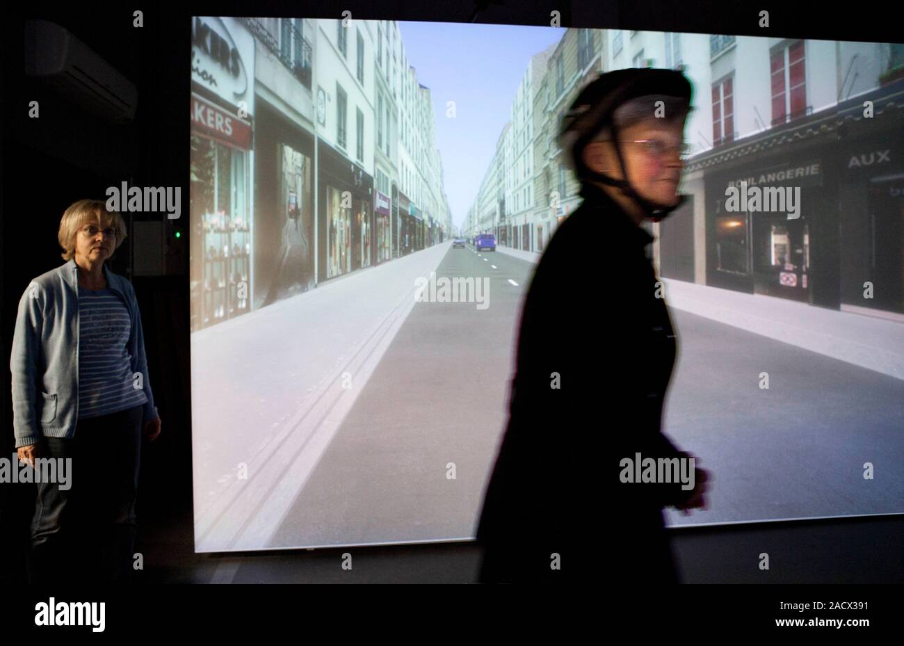 Road safety simulation. Researcher watching an elderly woman crossing a ...