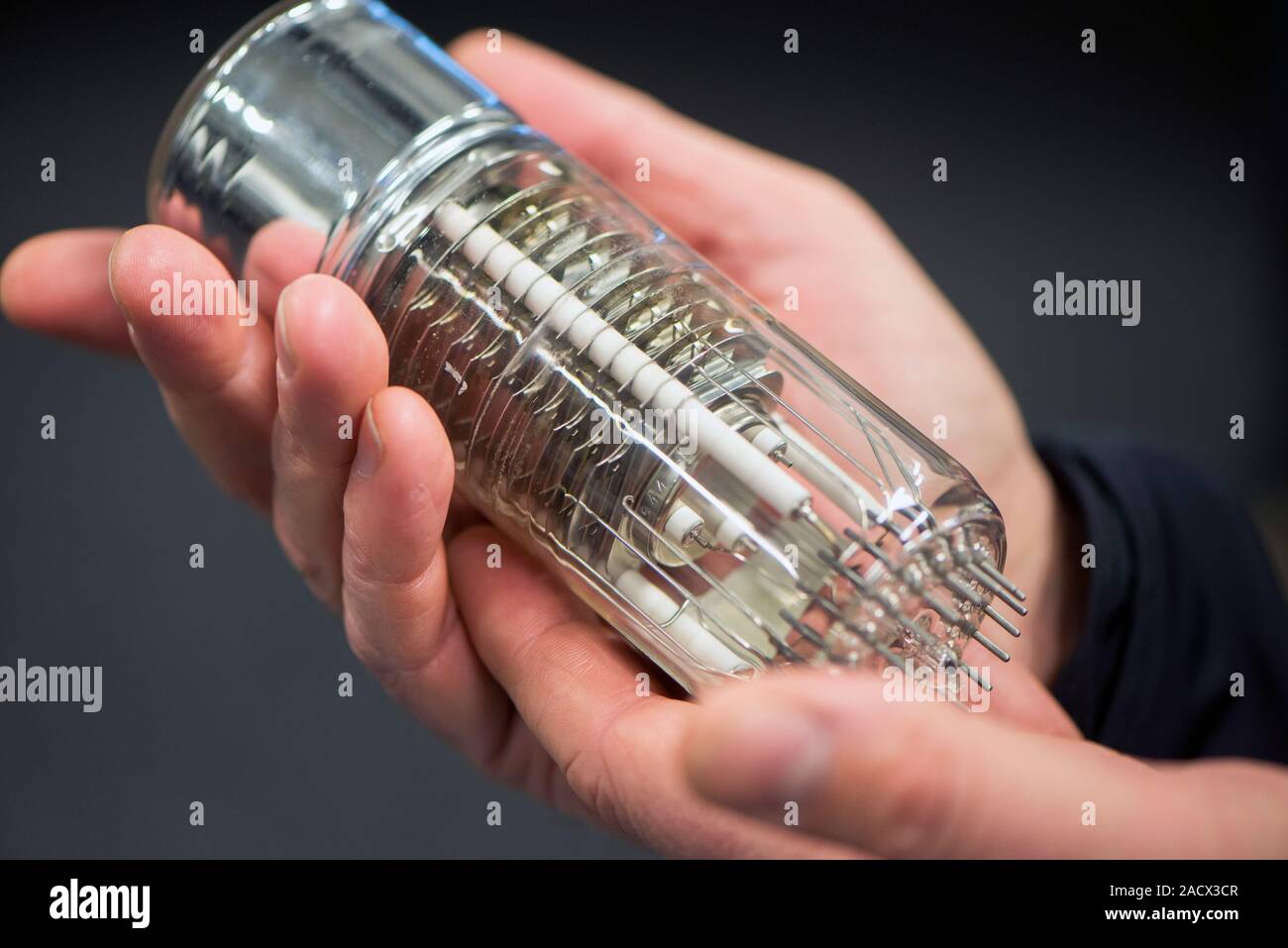 Photomultiplier tube. Hand holding a photomultiplier tube which is used ...