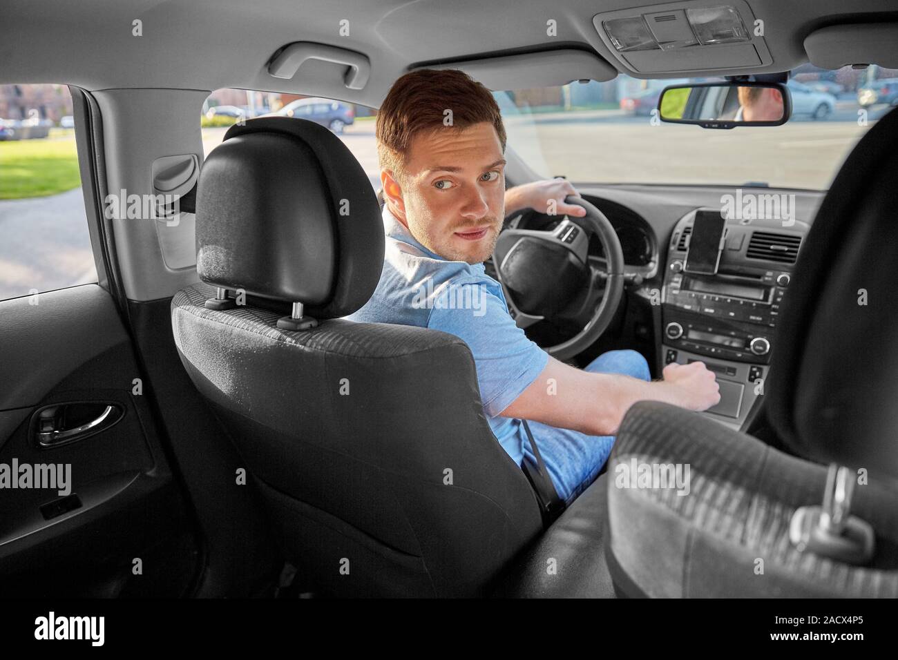 transport, vehicle and driving concept - man or car driver looking back ...