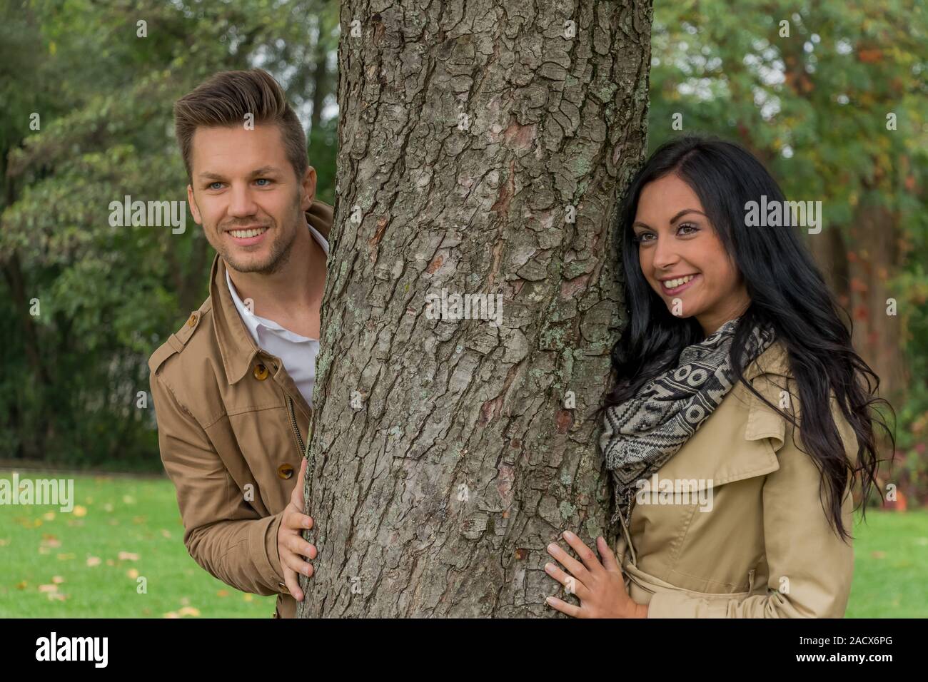 A couple in love behind a tree Stock Photo - Alamy