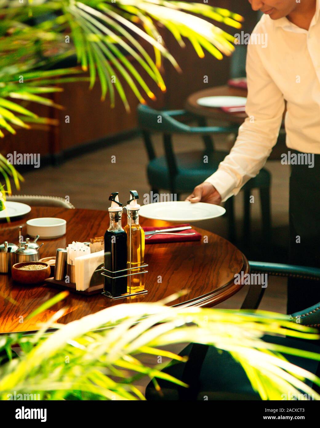 the waiter serves a table with a white service Stock Photo - Alamy