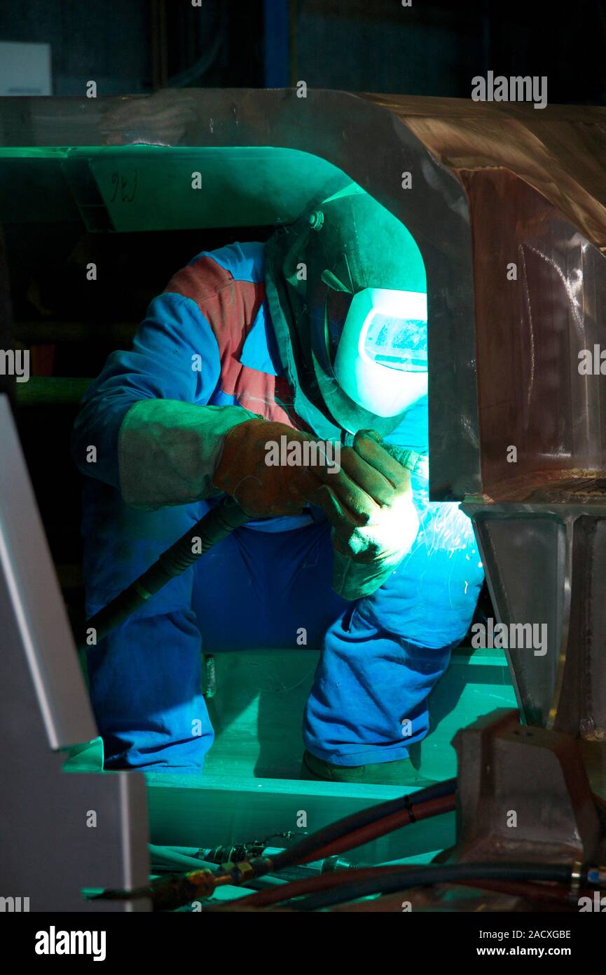 Welding in train construction. Skilled worker welding the chassis of a ...