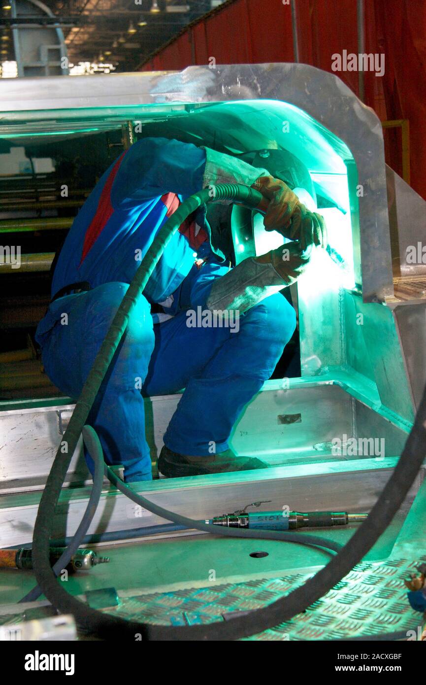 Welding in train construction. Skilled worker welding the chassis of a ...