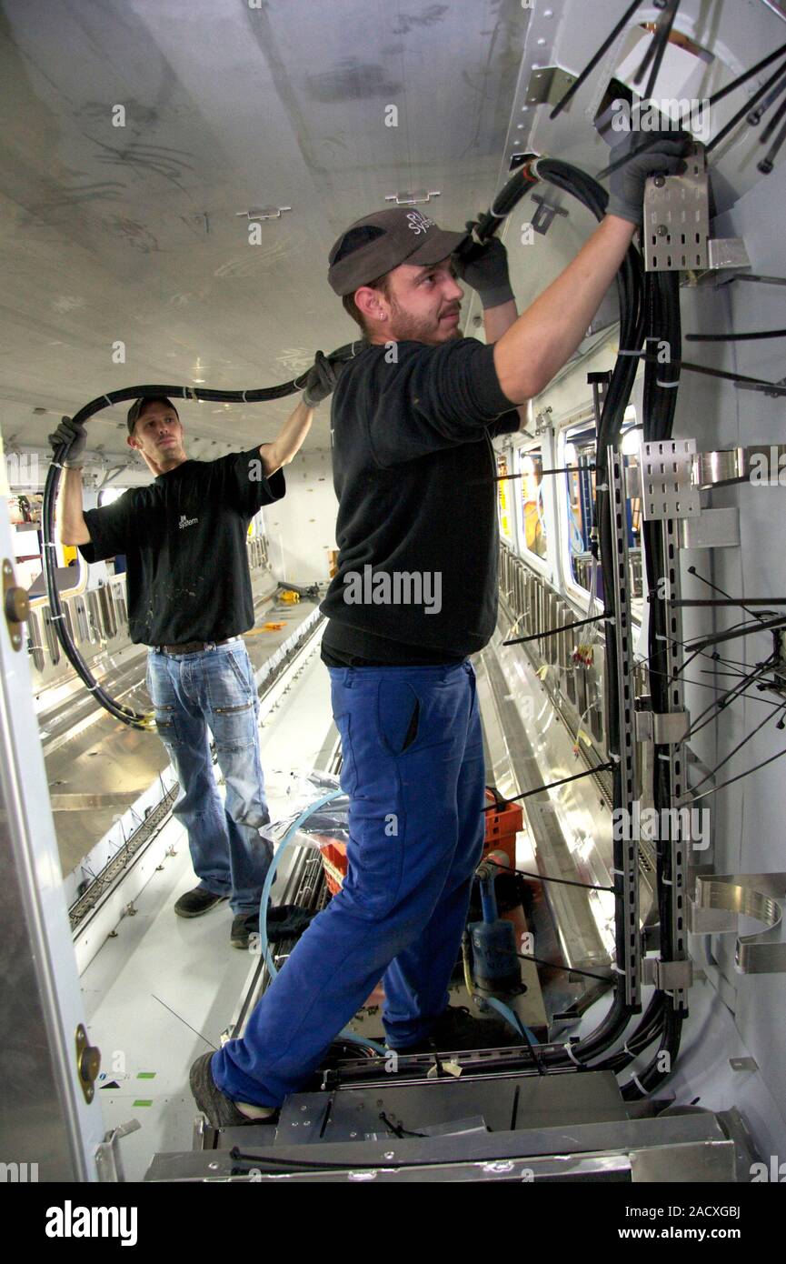 Electric wiring in train construction. Skilled workers installing ...