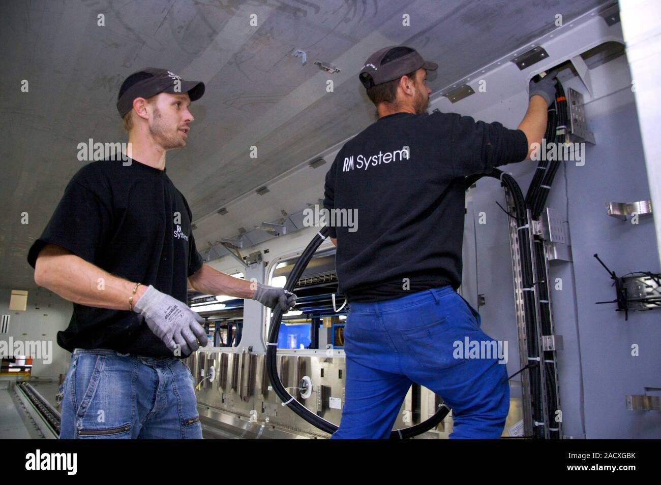 Electric wiring in train construction. Skilled workers installing ...