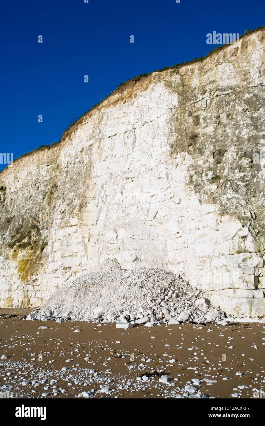 Chalk cliffs above a sandy beach with a pile of fallen chalk at the ...