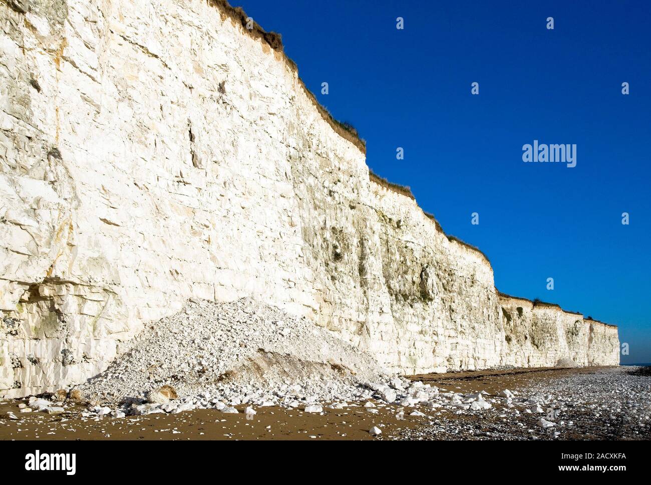 Chalk cliffs above a sandy beach with a pile of fallen chalk at the ...