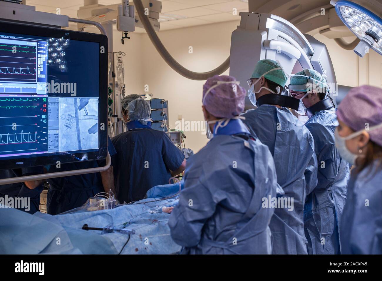 Cardiac catheterization. Surgeons using X-rays for guidance as they ...