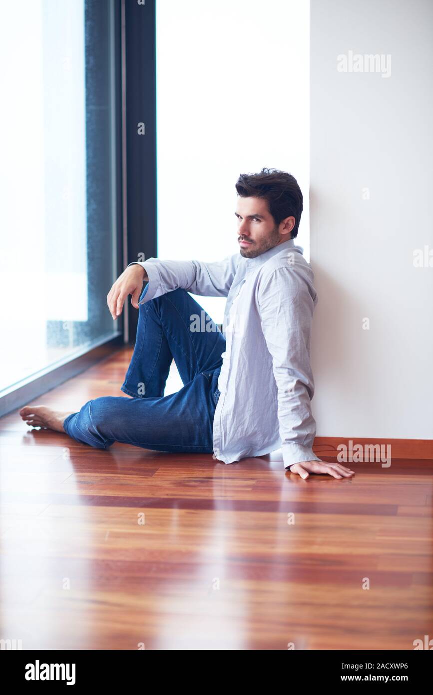 relaxed young man drink first morning coffee withh rain drops on window ...