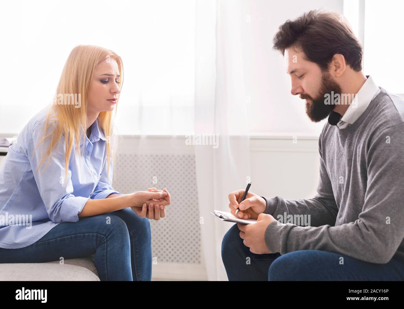 Male therapist taking notes, listening to female patient Stock Photo ...