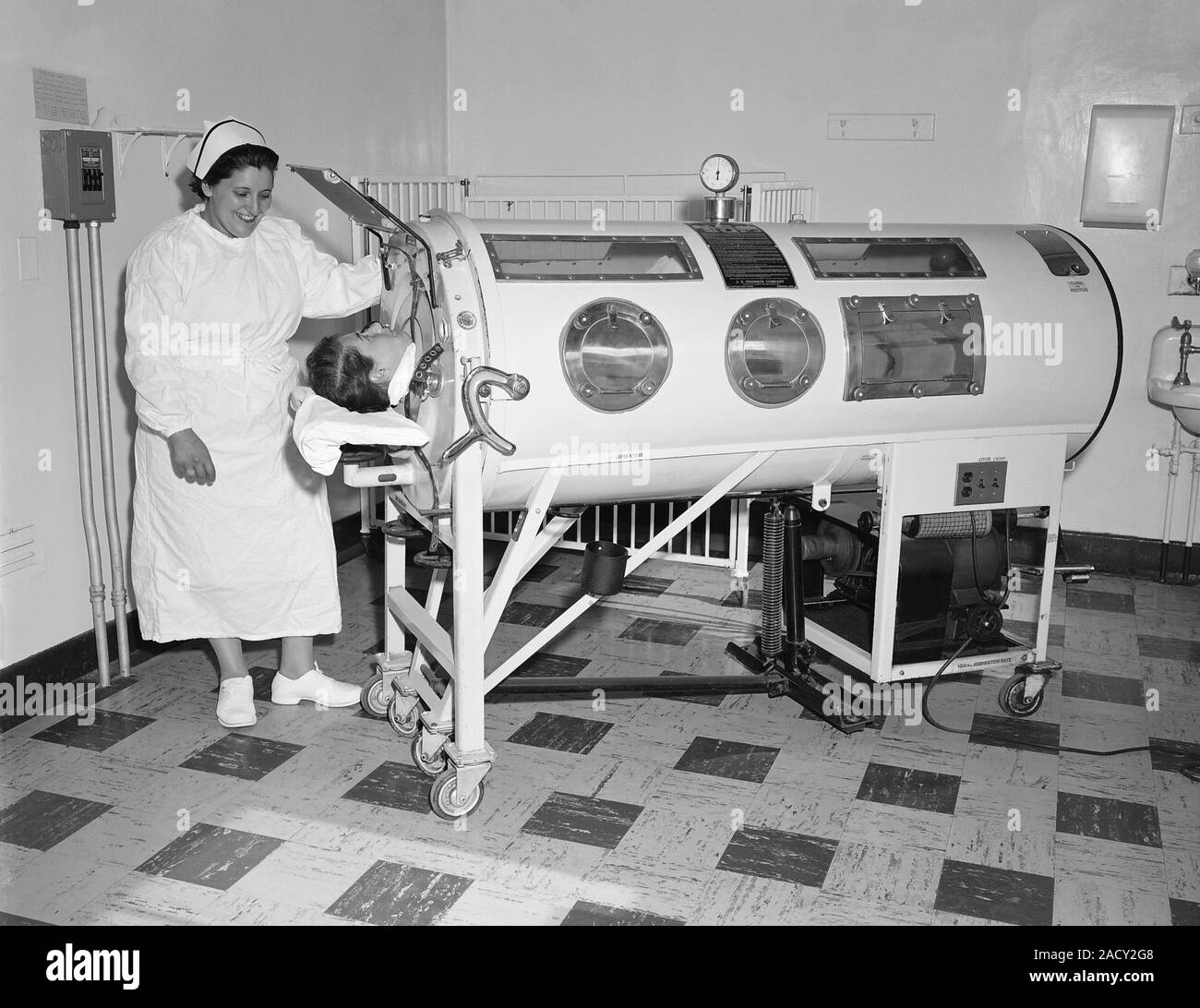 Iron lung. Nurse with a male polio patient inside an Emerson respirator ...