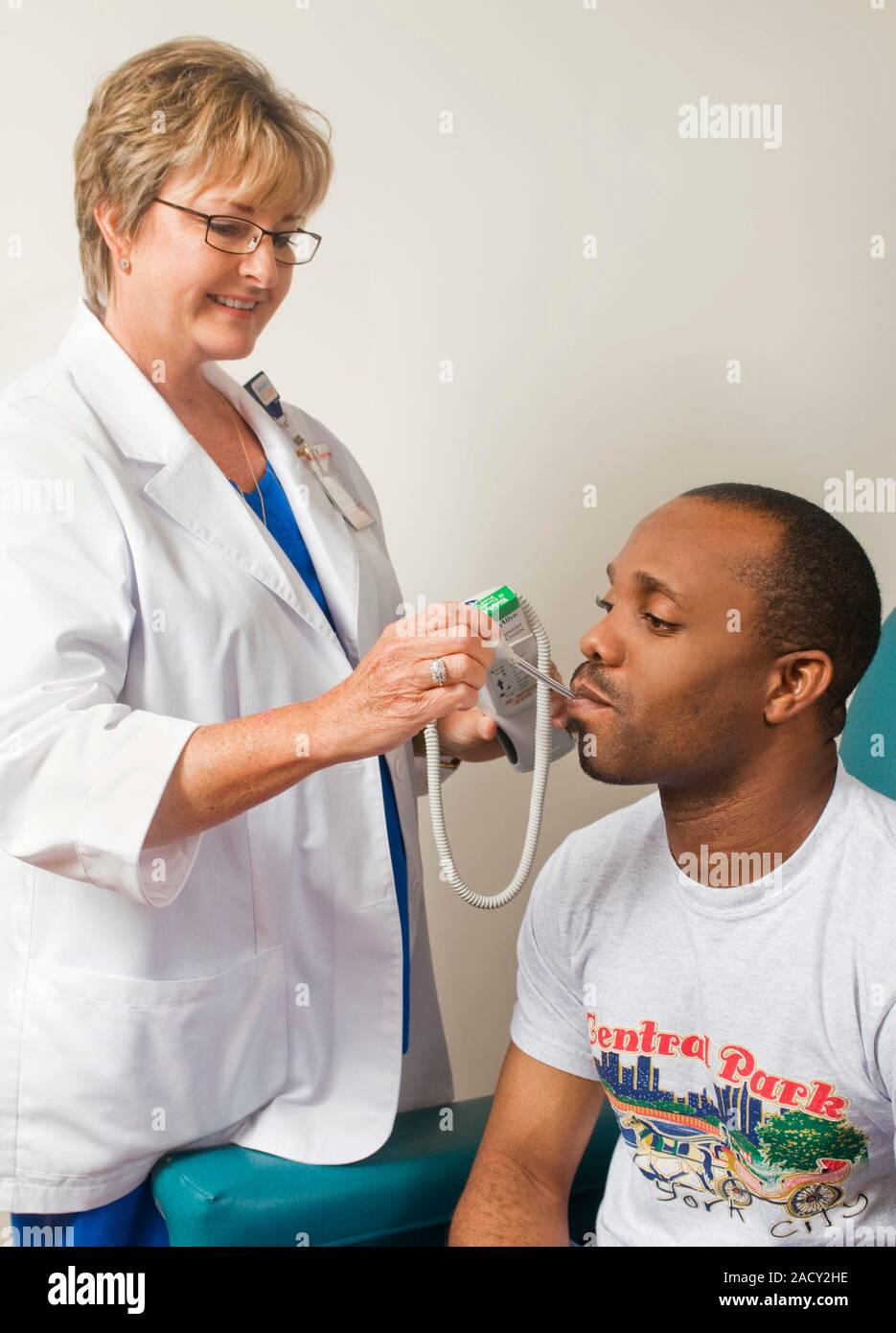 Taking a man's temperature. Doctor using an oral thermometer to take the body temperature of a ...
