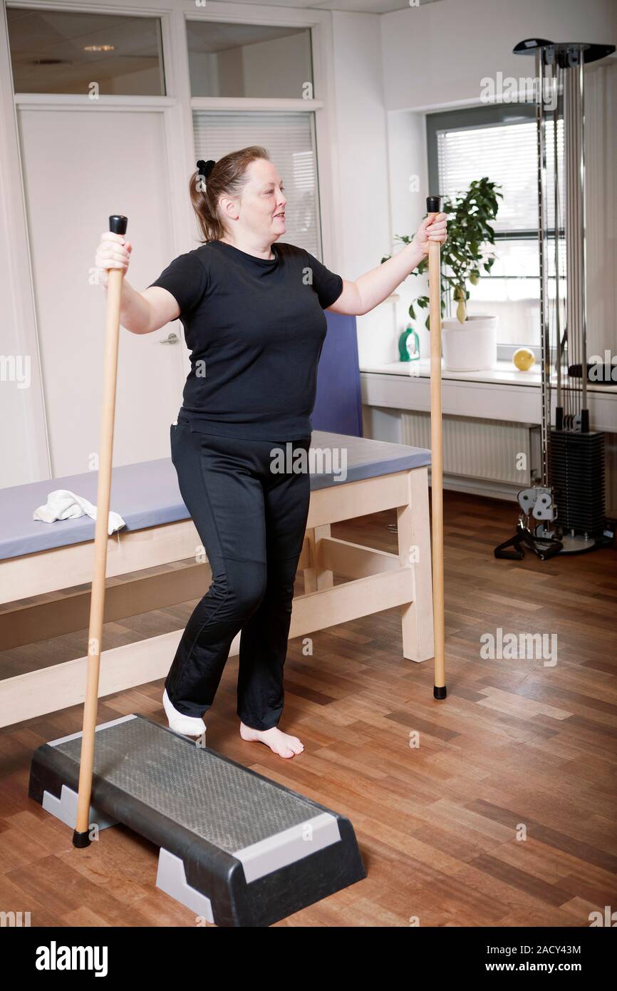 Leg injury physiotherapy. Female patient doing one-leg-stand training ...