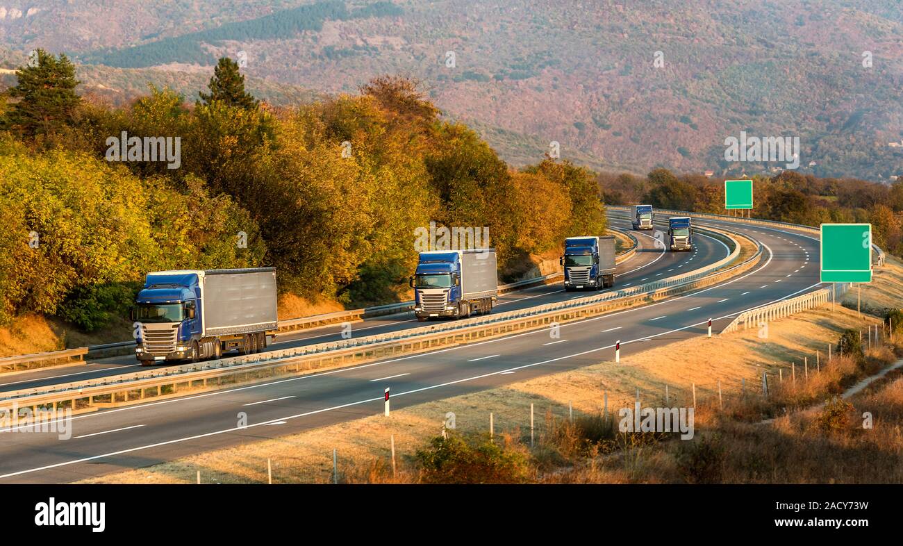 Convoy of blue lorry trucks on a highway. Highway transportation with ...