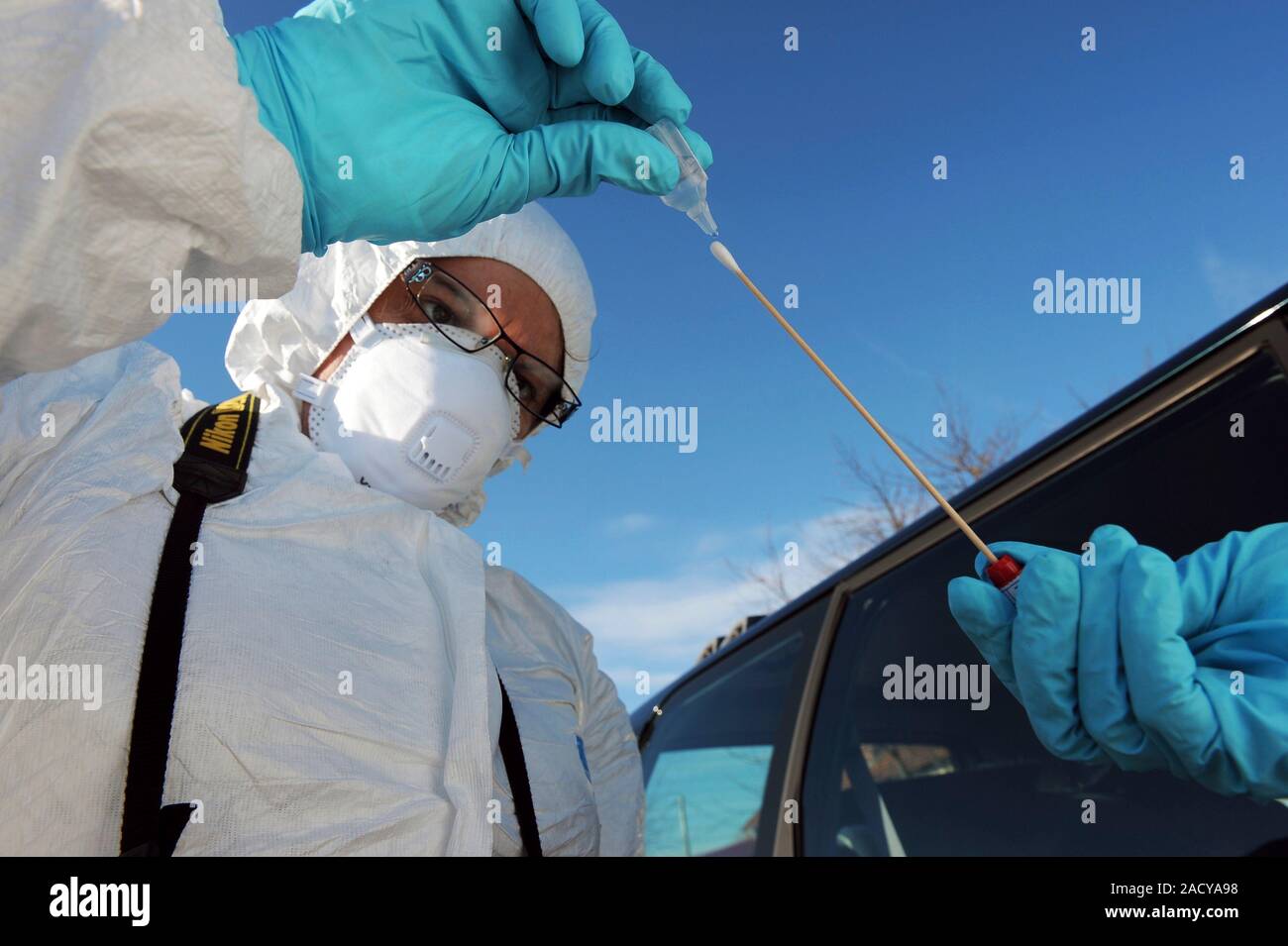 Policeman collecting a blood sample during forensic training ...