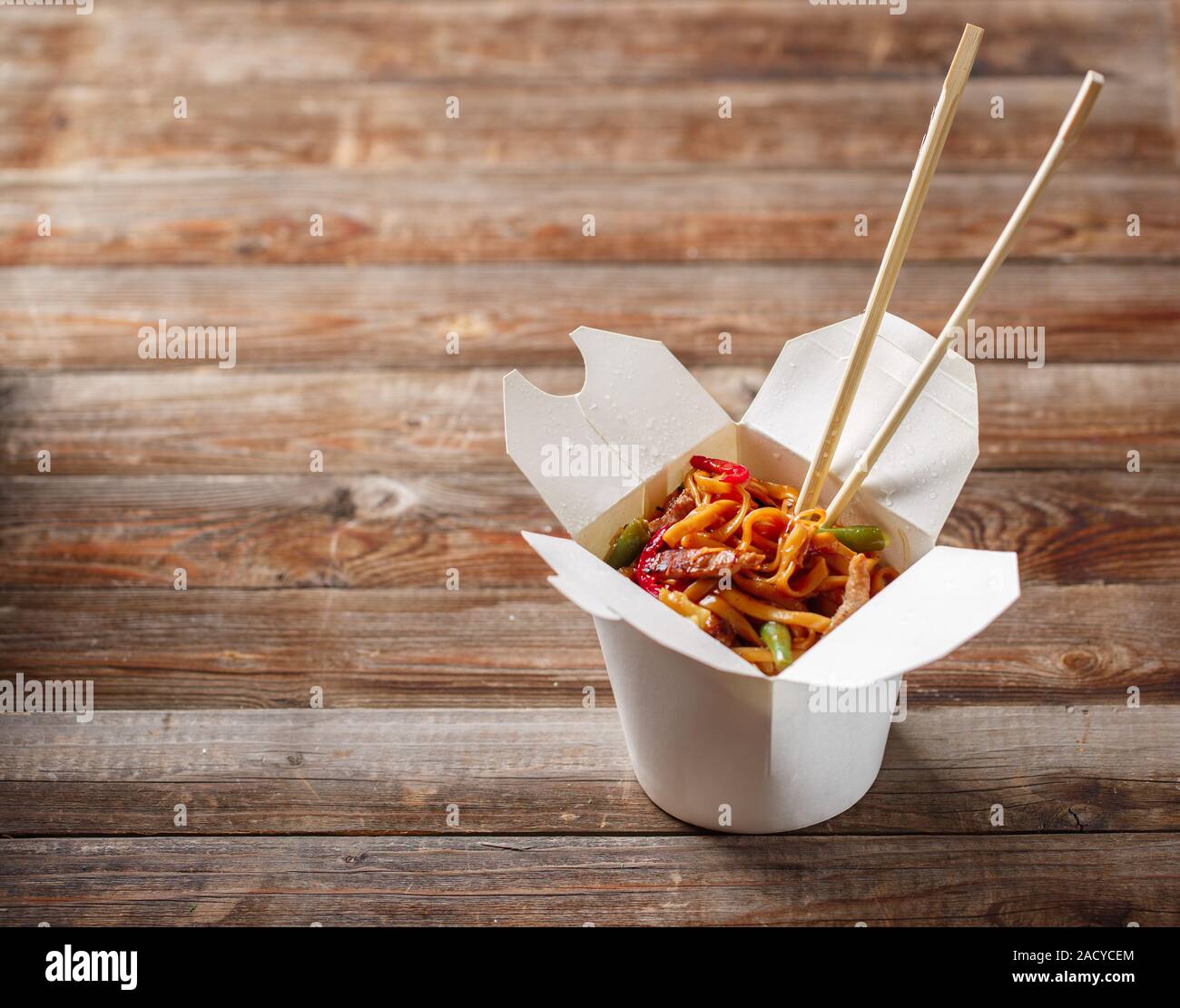 Noodles with pork and vegetables in take-out box on wooden table Stock ...