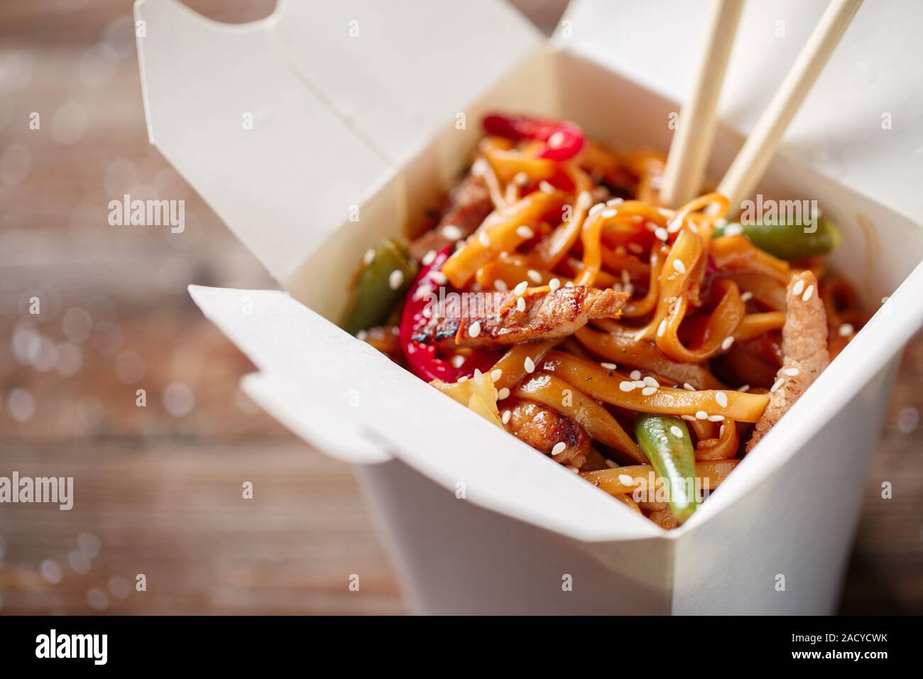 Noodles with pork and vegetables in take-out box on wooden table Stock ...