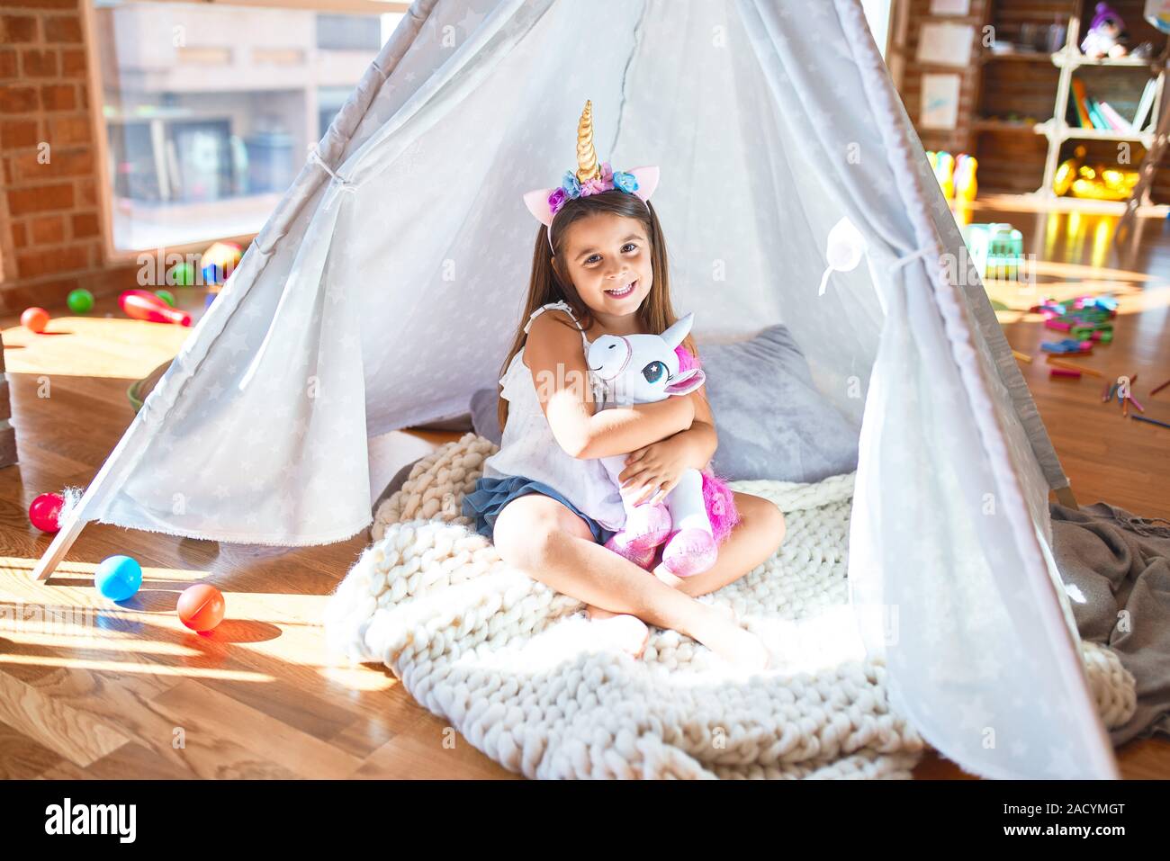 Adorable toddler sitting on the floor inside tipi around lots of toys ...