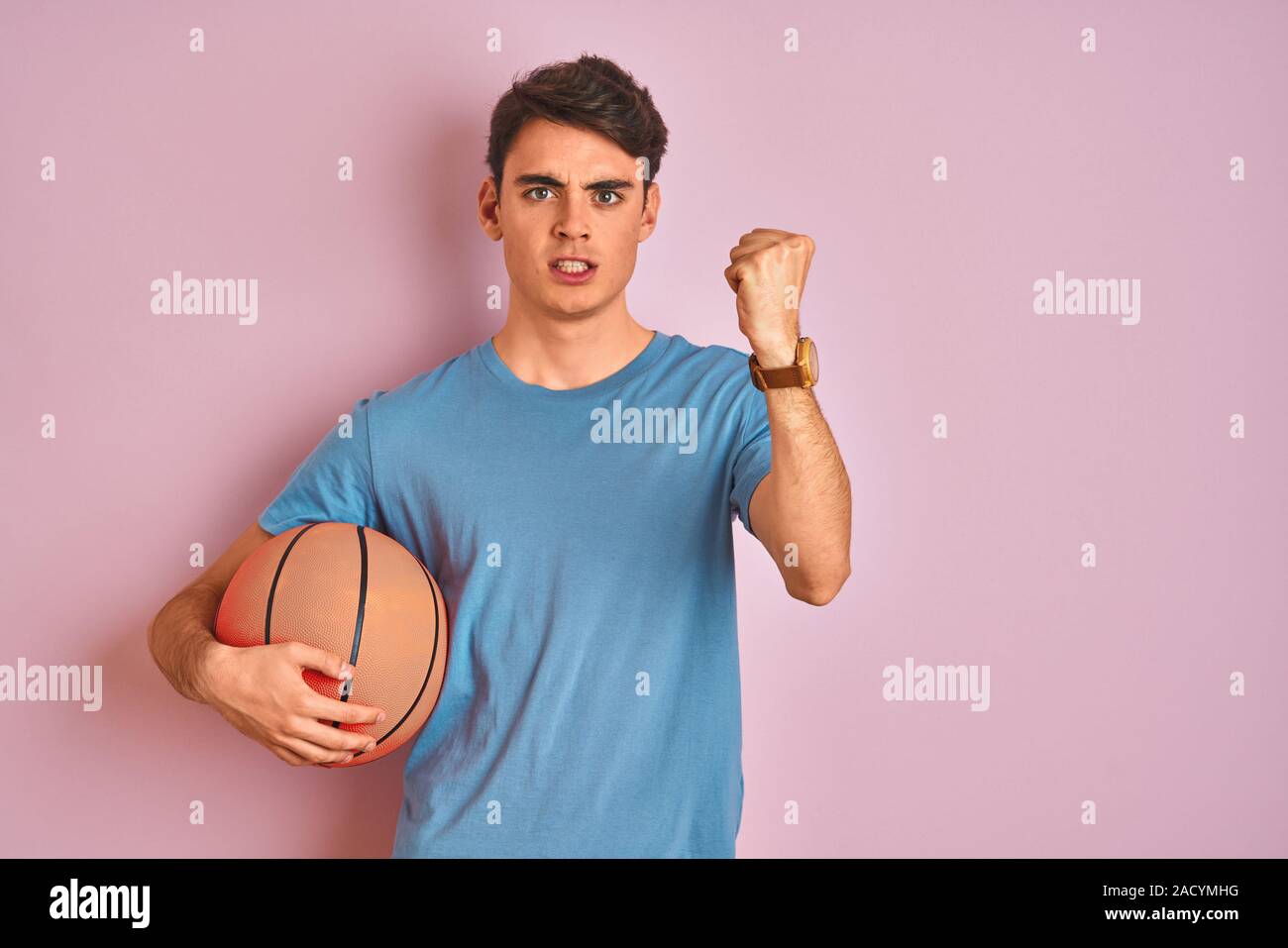 Teenager boy holding professional basket ball over isolated pink ...