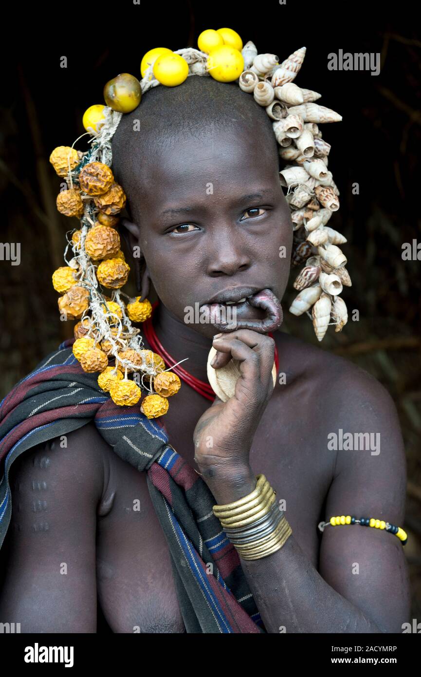 The image shows a young Mursi girl who has removed her lip plate. In recent times it is evident ...