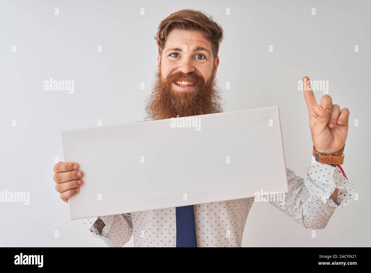Young redhead irish man holding banner standing over isolated white ...