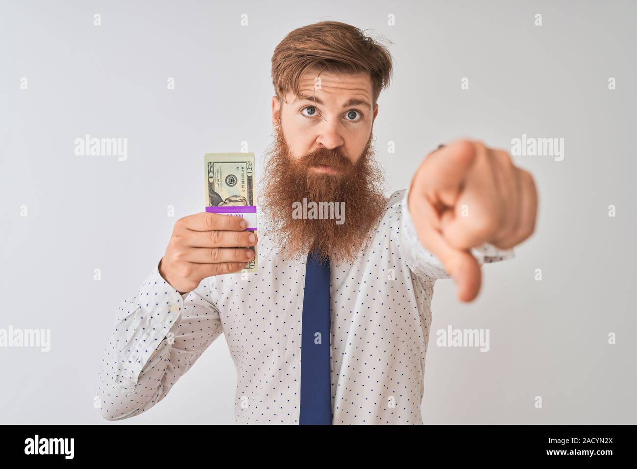 Young redhead irish businessman holding dollars standing over isolated ...