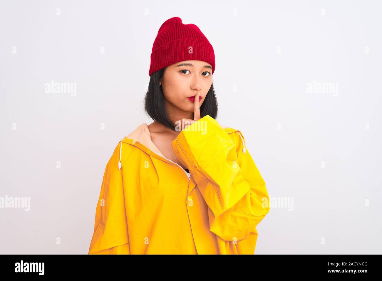 Young beautiful chinese woman wearing raincoat and wool cap over ...