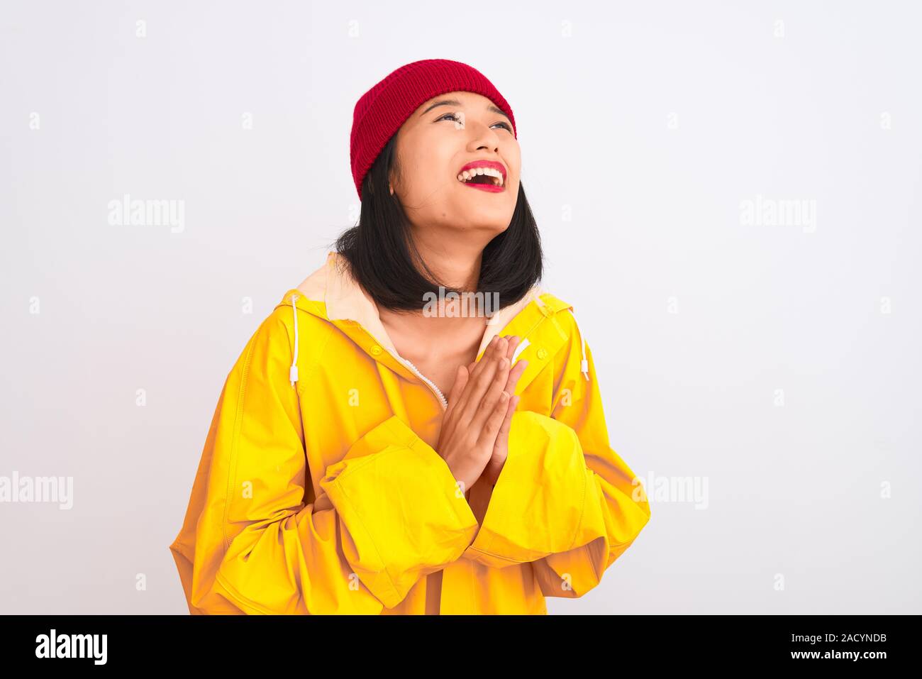 Young beautiful chinese woman wearing raincoat and wool cap over ...