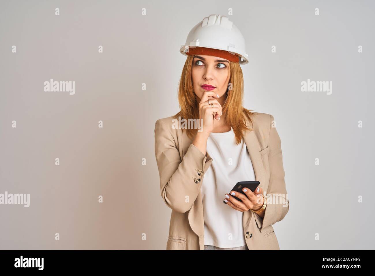 Young caucasian engineer woman using smartphone and wearing safety ...