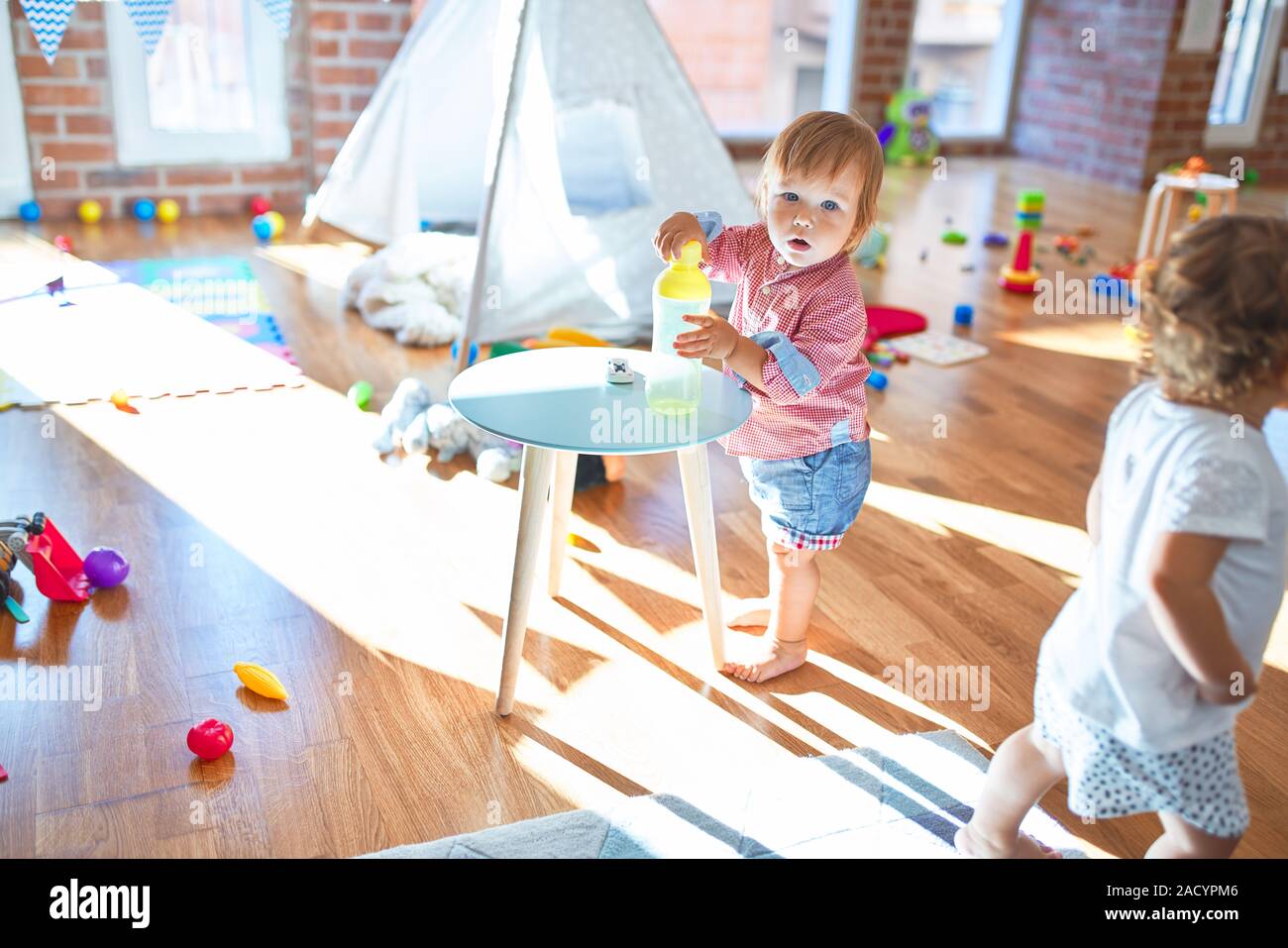 Adorable toddlers playing around lots of toys at kindergarten Stock ...