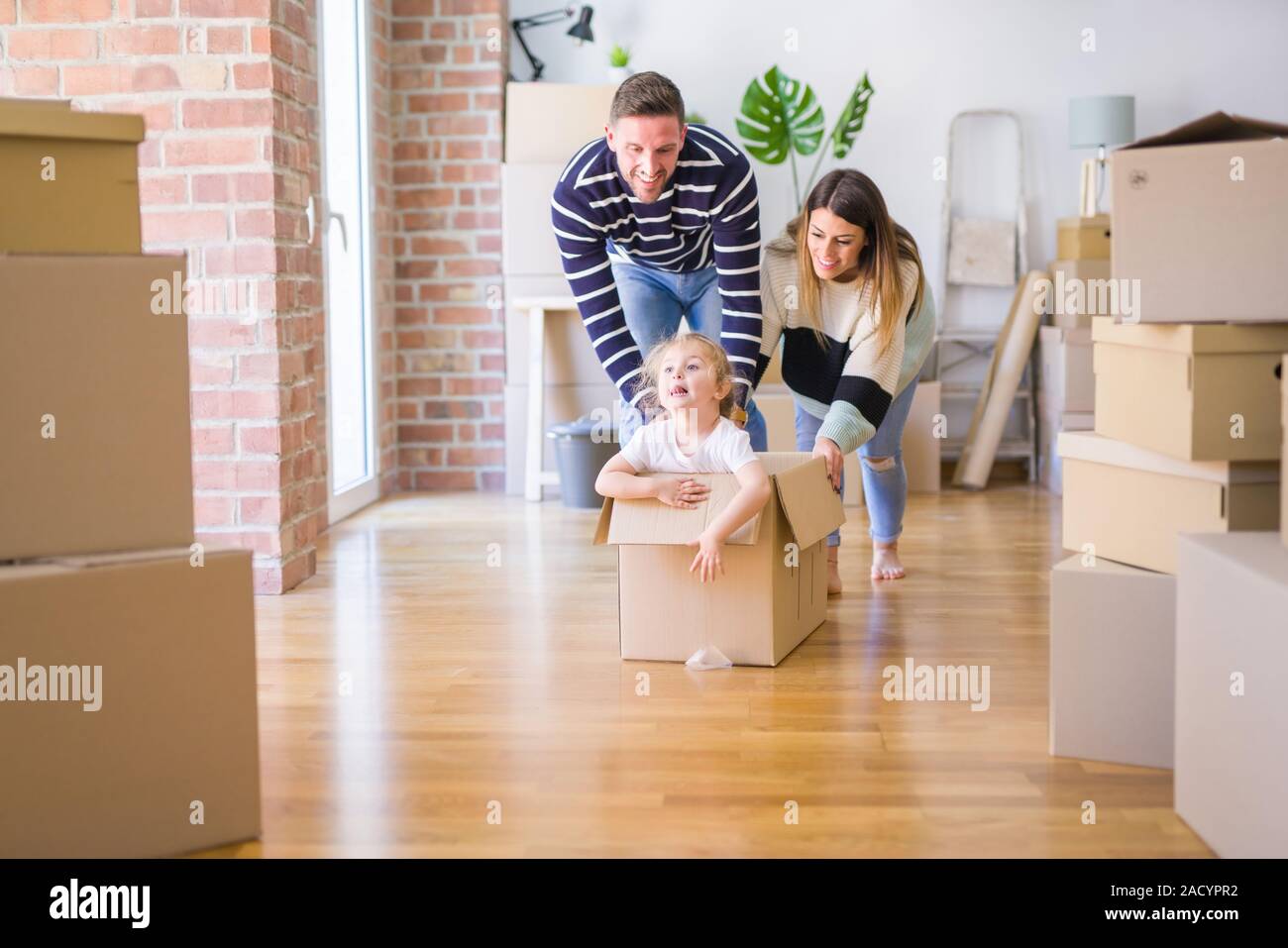 Beautiful famiily, kid playing with his parents riding cardboard fanny ...