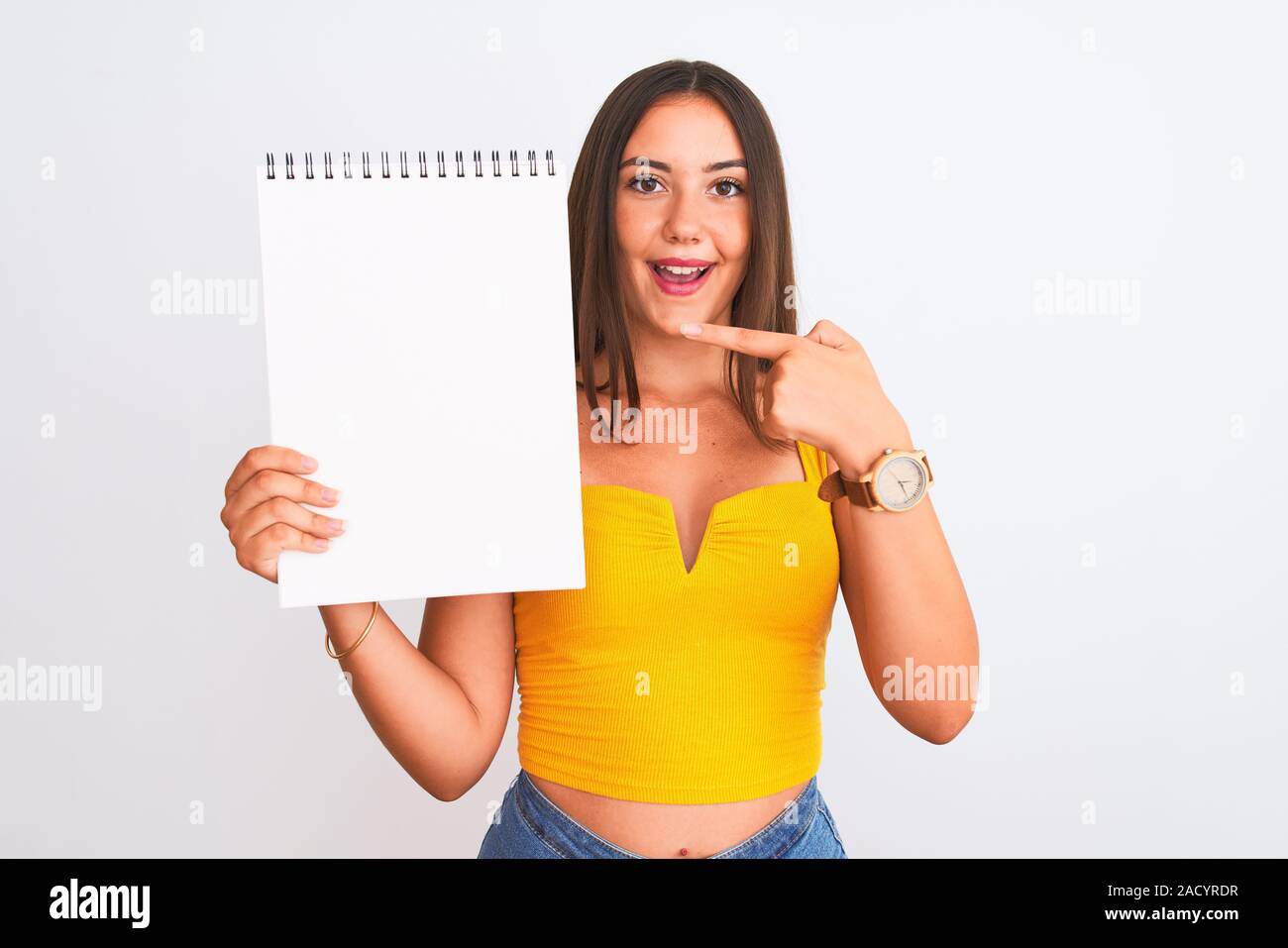 Young beautiful student girl holding notebook standing over isolated ...