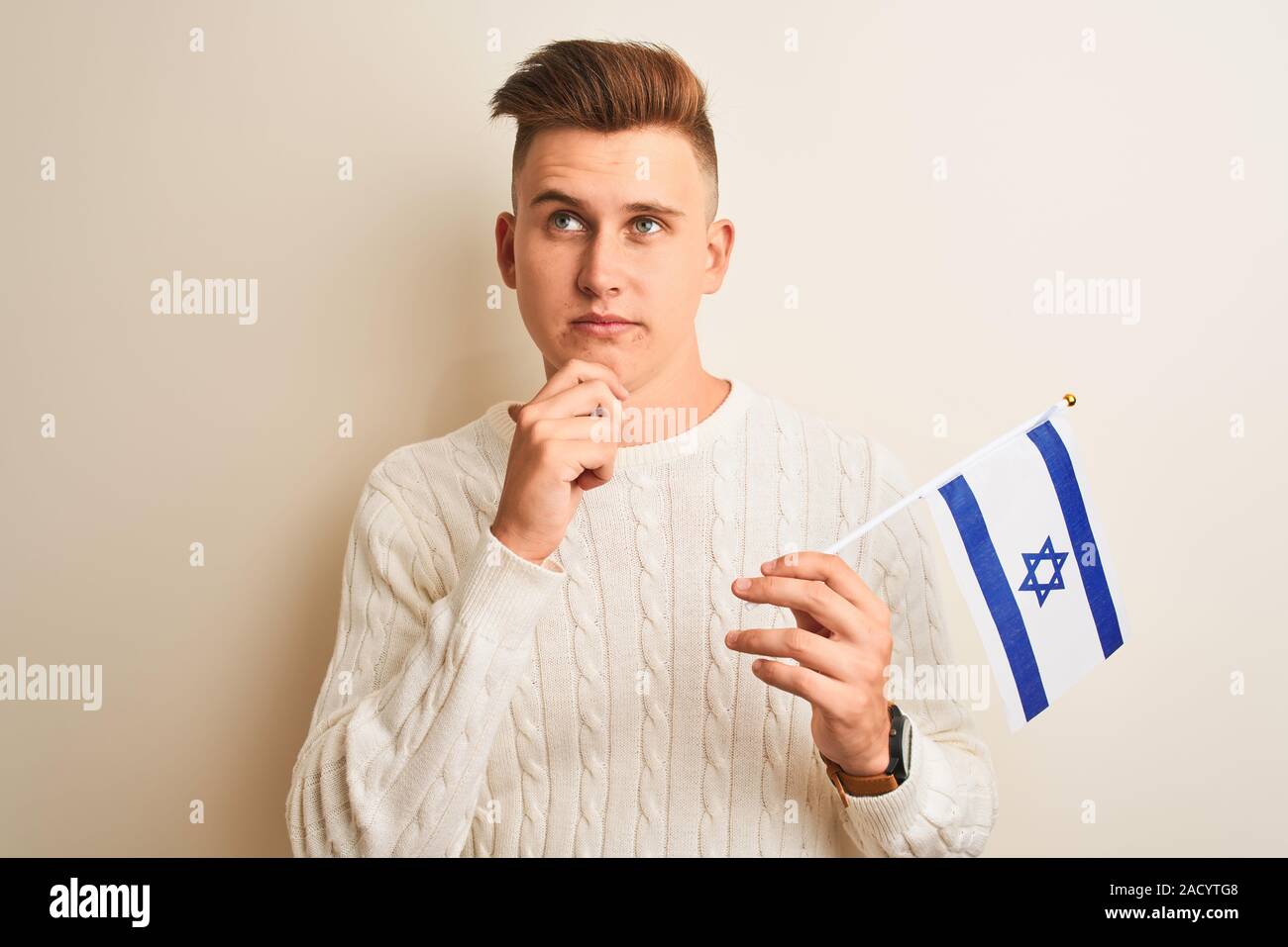 Young handsome man holding Israel Israeli flag over isolated white ...