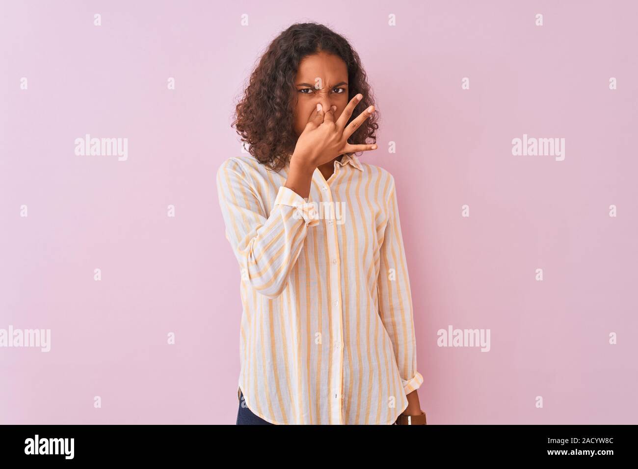 Young brazilian woman wearing striped shirt standing over isolated pink ...