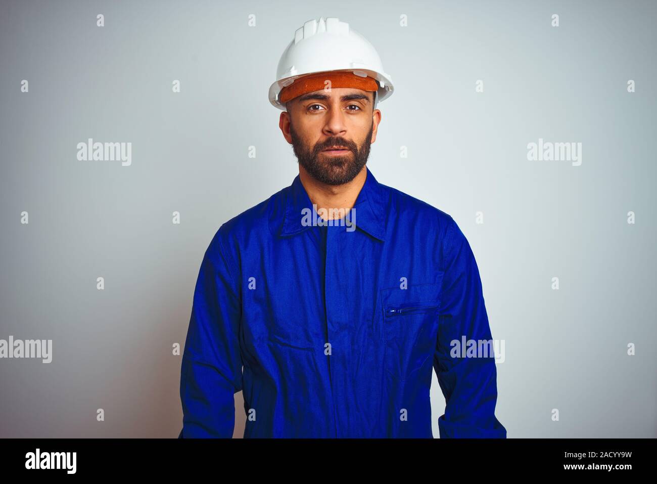 Handsome indian worker man wearing uniform and helmet over isolated ...
