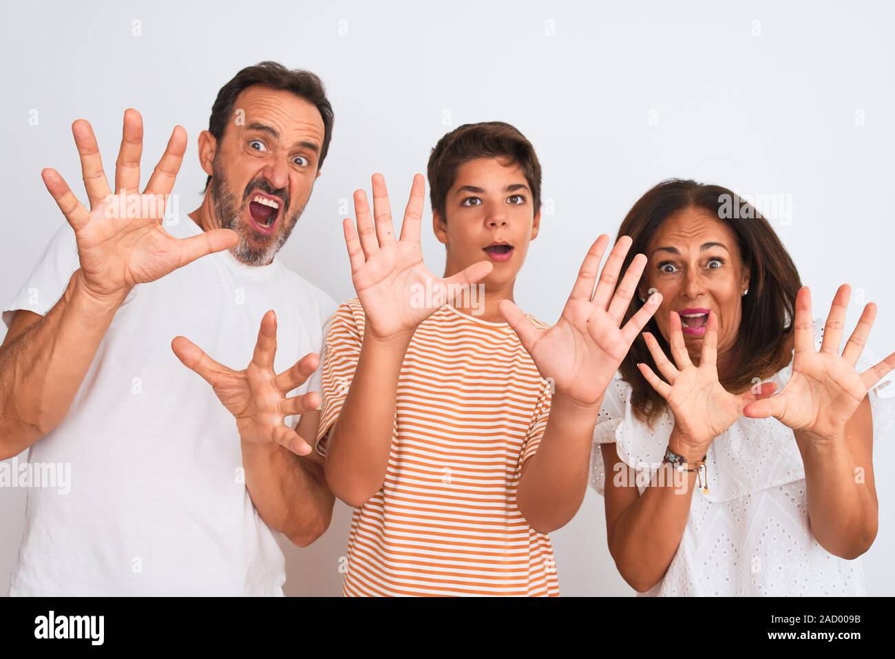 Family of three, mother, father and son standing over white isolated ...