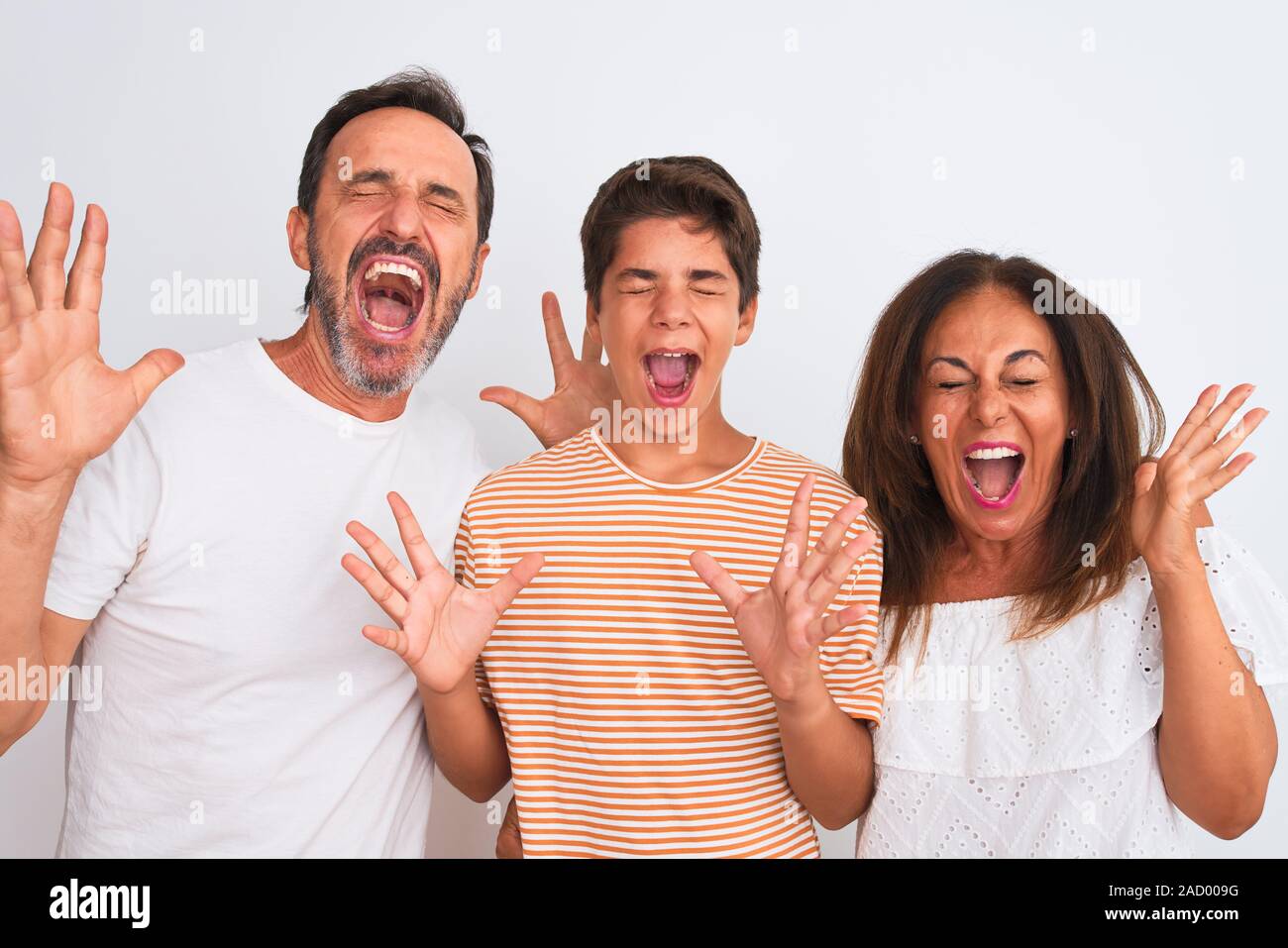 Family of three, mother, father and son standing over white isolated ...