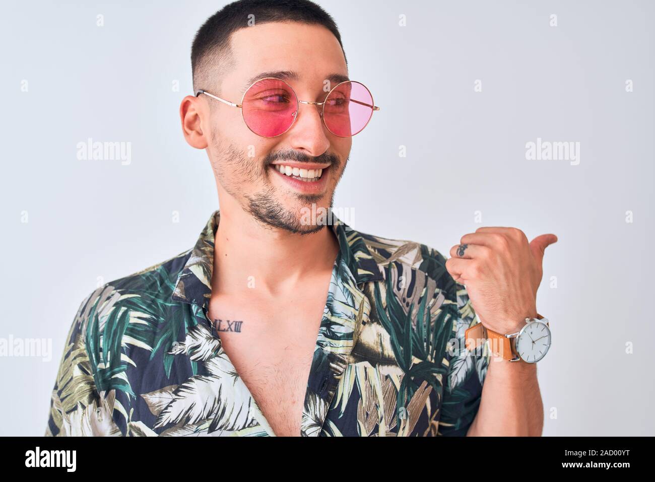 Young handsome man wearing Hawaiian sumer shirt and pink sunglasses ...