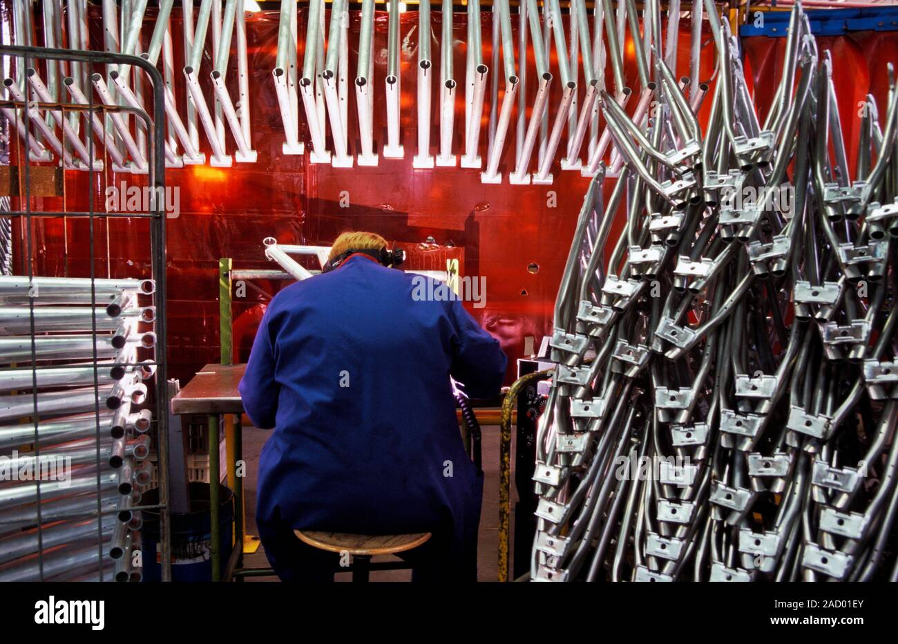 Bike production. Factory worker welding frames for bicycles Stock Photo ...
