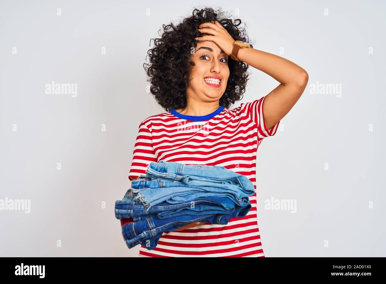 Young arab shopkeeper woman with curly hair holding jeans over isolated ...