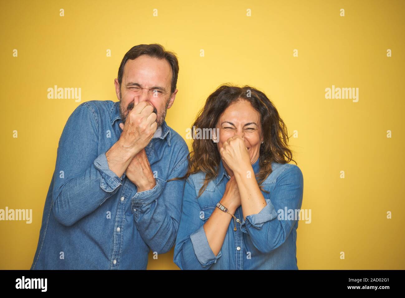 Beautiful middle age couple together standing over isolated yellow ...