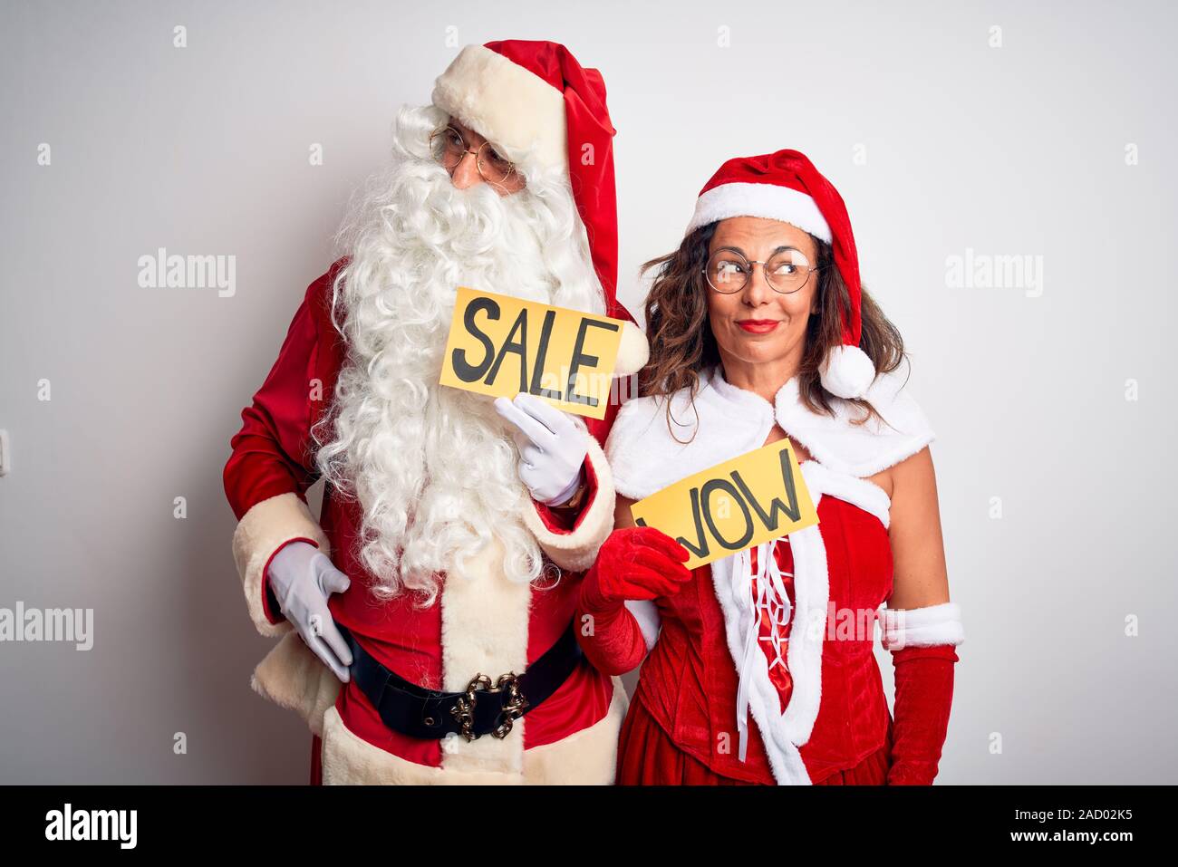 Couple wearing Santa costume holding wow and sale banner over isolated ...