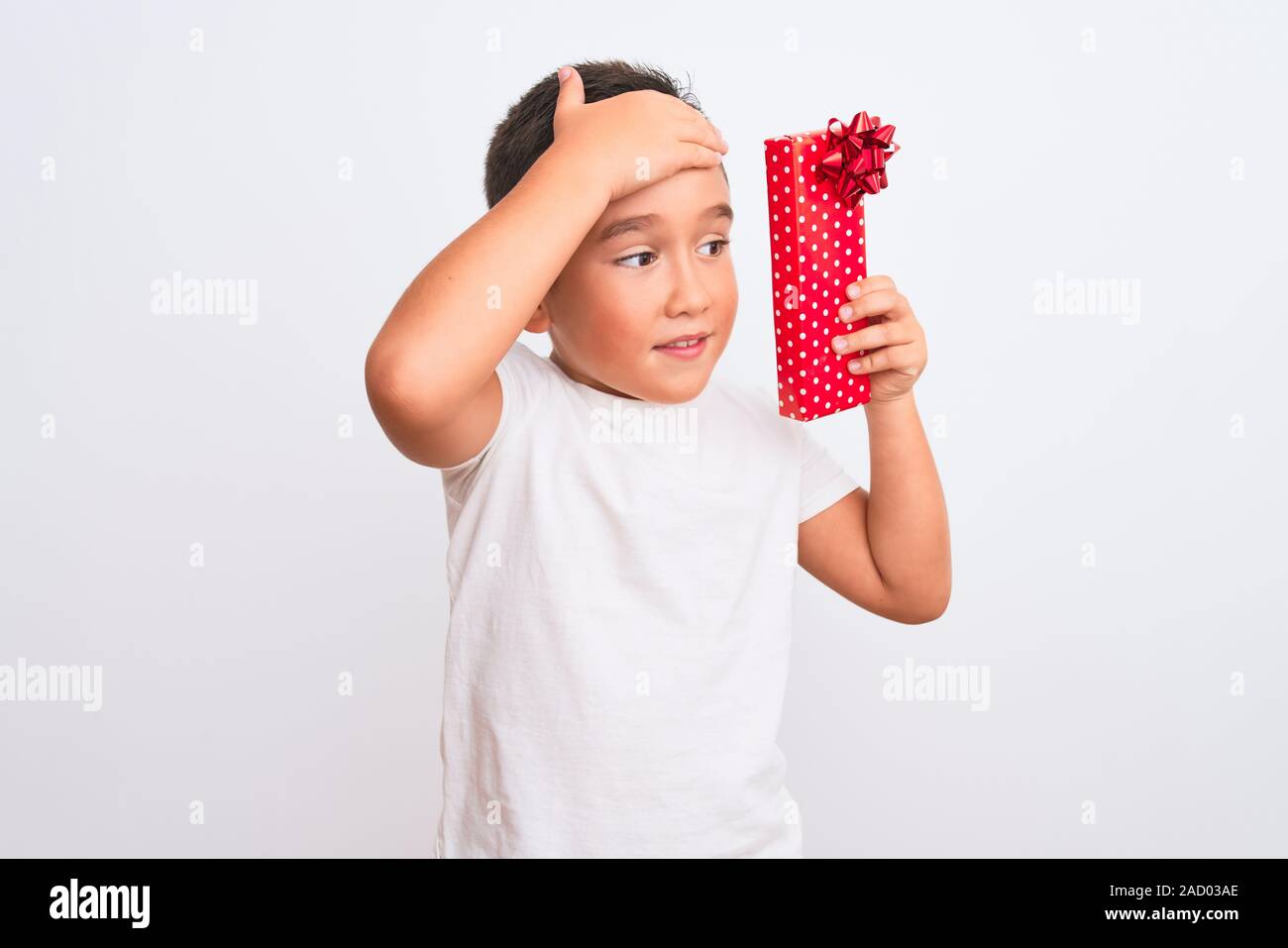 Beautiful kid boy holding birthday gift standing over isolated white ...